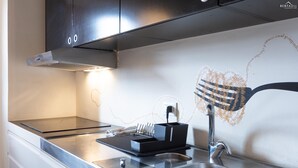 Uma cozinha moderna com eletrodomésticos de aço inoxidável, painel de fundo preto e torneira fixada na parede.