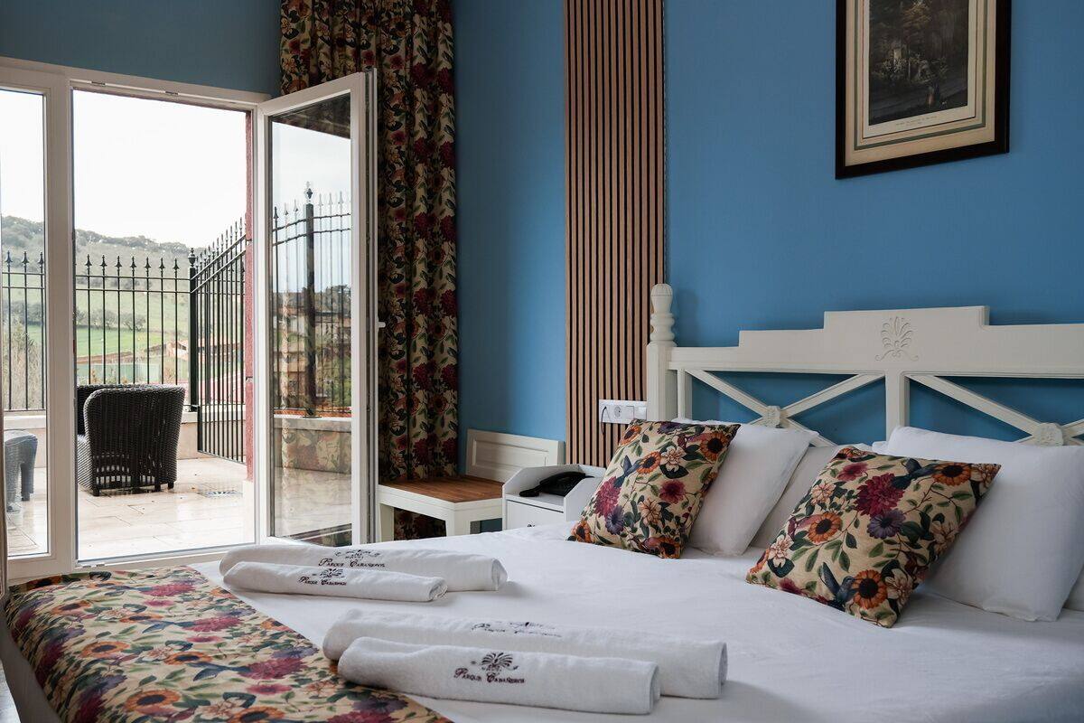 Quarto de hotel com cama, escrivaninha, cadeira e vista para o exterior.