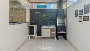 Cozinha compacta com forno embutido, pia pequena e janela com cortinas estampadas.