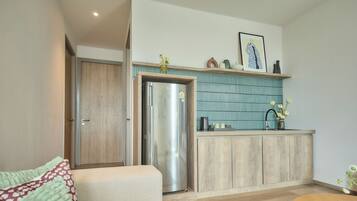 Uma cozinha compacta com geladeira embutida, armários de madeira e painel de azulejos.