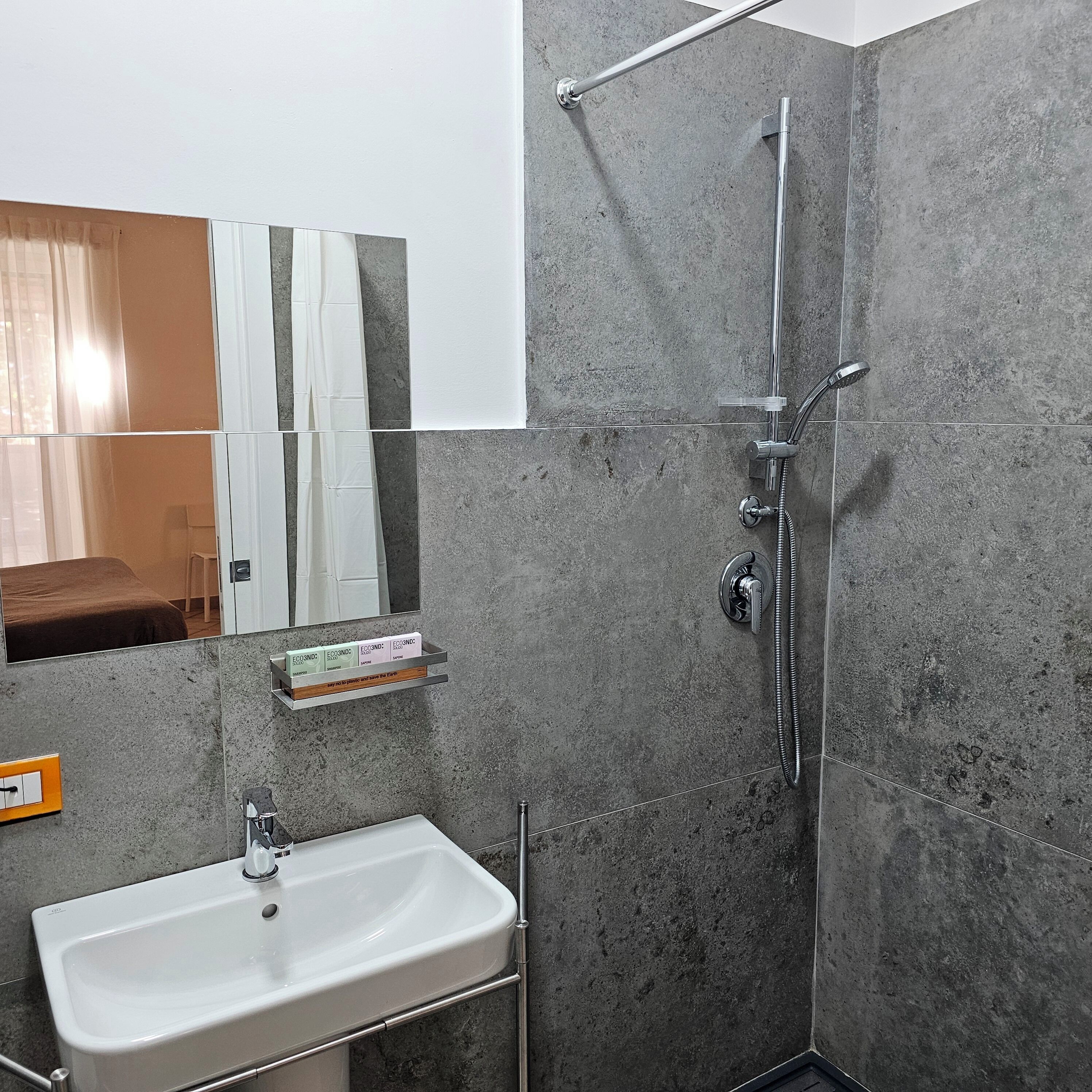 Uma casa de banho moderna com chuveiro, lavatório e espelho.