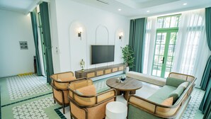 Uma sala de estar moderna com um sofá, duas poltronas, uma mesa de centro e uma televisão de tela plana na parede.