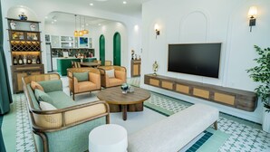 Uma sala de estar moderna com um sofá, poltronas, uma mesa de centro e uma televisão.