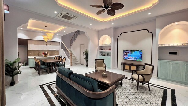 Uma sala de estar moderna com sofá, mesa de centro e televisão. Existe uma escada que leva a um andar superior.