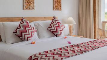 Quarto de hotel com uma cama grande, painéis decorativos na parede, uma mesa de cabeceira com abajur e vista para o exterior através de uma janela com cortinas.