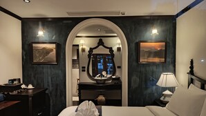 Quarto de hotel com cama, escrivaninha, espelho e duas luminárias.