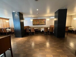 Uma sala de jantar espaçosa com piso de madeira, mesas e cadeiras.