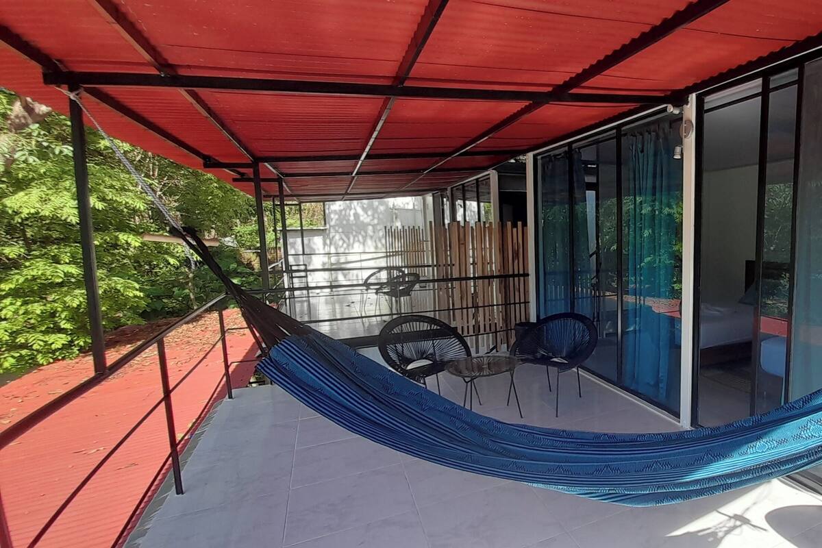 Varanda coberta com rede, portas de vidro e vista para o verde.