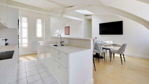 Uma cozinha moderna com armários brancos, uma ilha central e uma área de refeições com mesa e cadeiras.