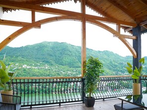 Um gazebo de madeira com vista para um rio e montanhas.