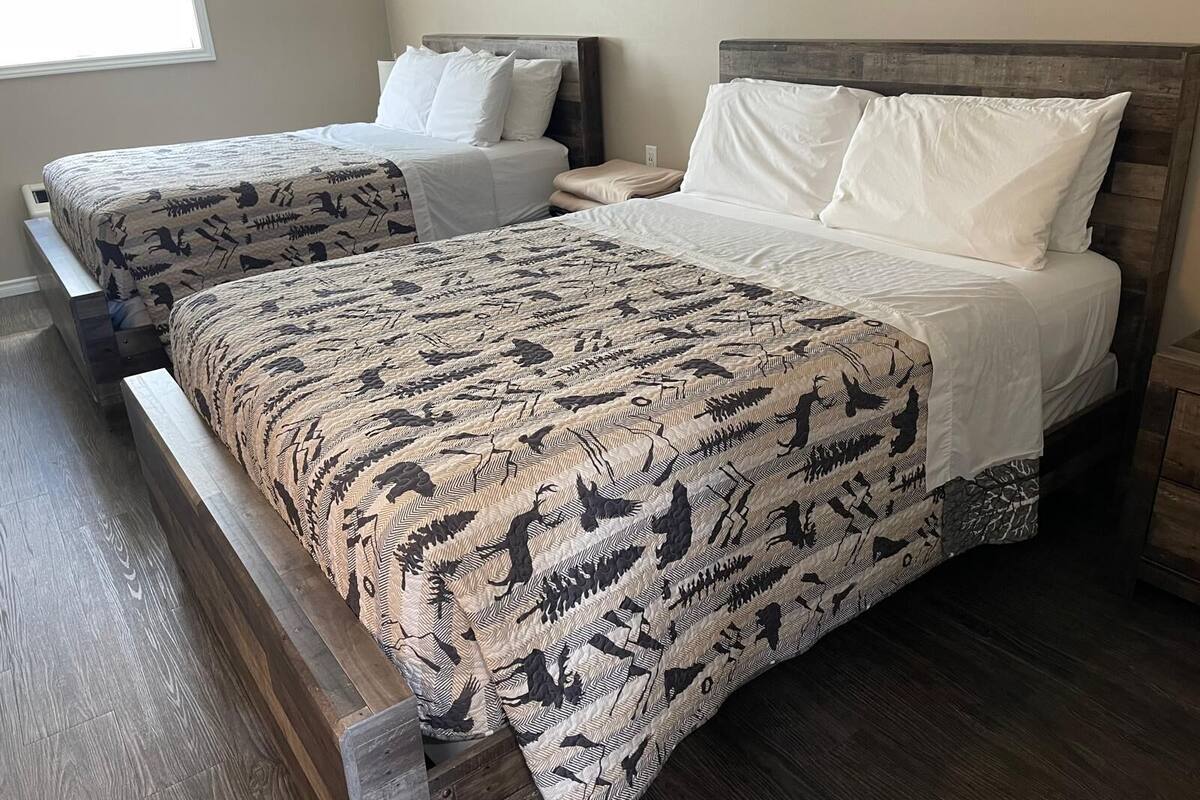 Quarto com duas camas, cada uma com colcha estampada e almofadas brancas.
