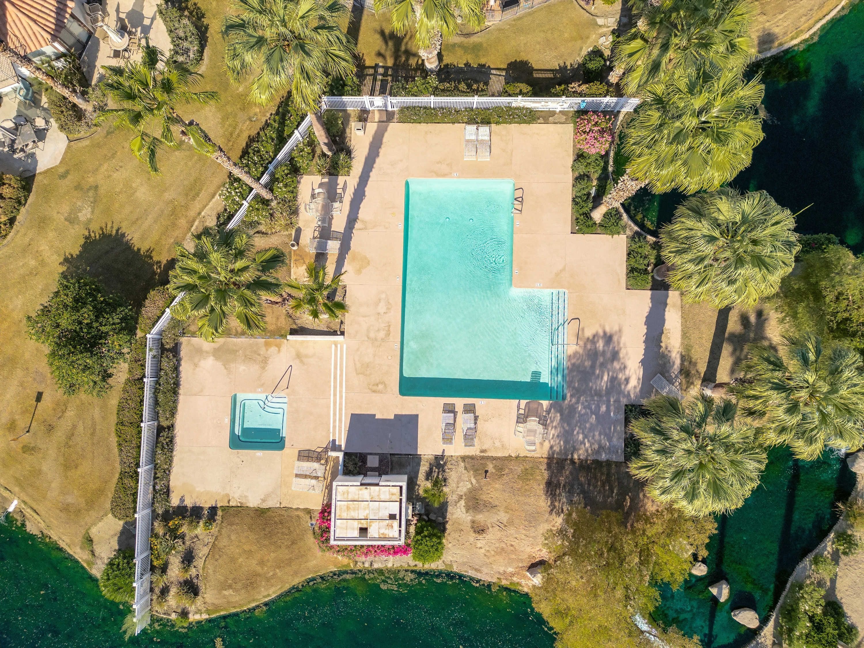 Vista aérea de um resort com piscina, espreguiçadeiras e um pequeno edifício.