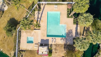 Vista aérea de um resort com piscina, espreguiçadeiras e um pequeno edifício.