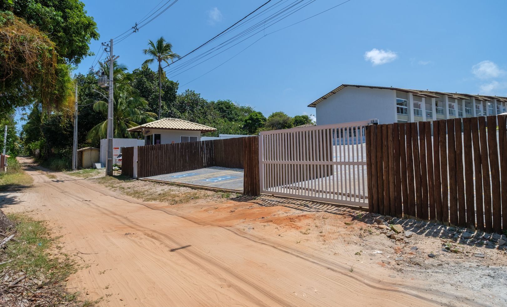 Uma propriedade murada com uma estrada de terra que leva a um edifício com telhado em telhas.