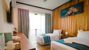 Quarto de hotel com duas camas, piso de madeira, televisão de tela plana, um quadro na parede e uma mesa com chaleira e xícaras.