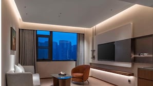 Uma sala de estar moderna com sofá, poltrona, mesa de centro e televisão de tela plana na parede.