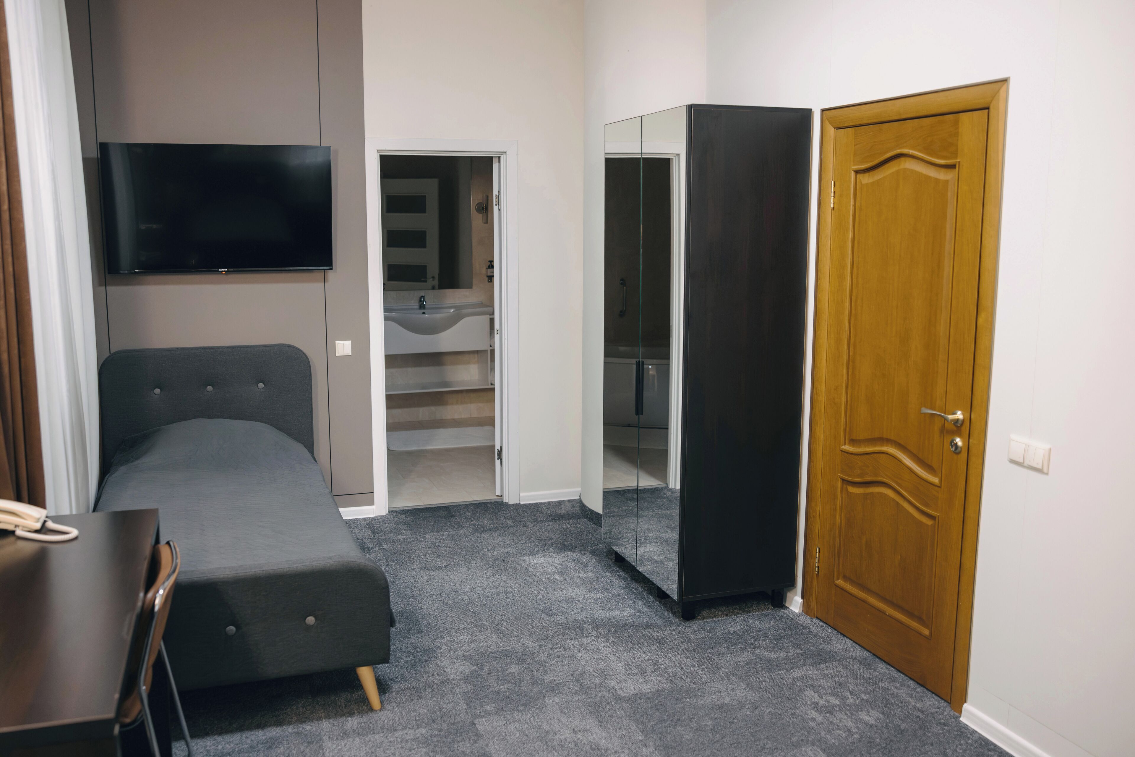 Quarto com cama, televisão, escrivaninha e guarda-roupa.