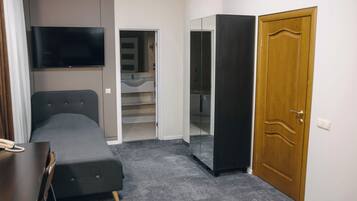Quarto com cama, televisão, escrivaninha e guarda-roupa.