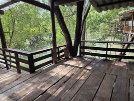 Um deck de madeira com guarda-corpo, com vista para um corpo d'água cercado por árvores.