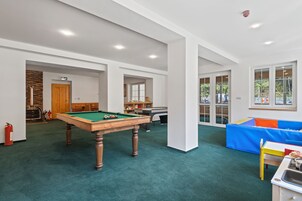 Um quarto com mesa de bilhar, espaço de recreação infantil e lareira.