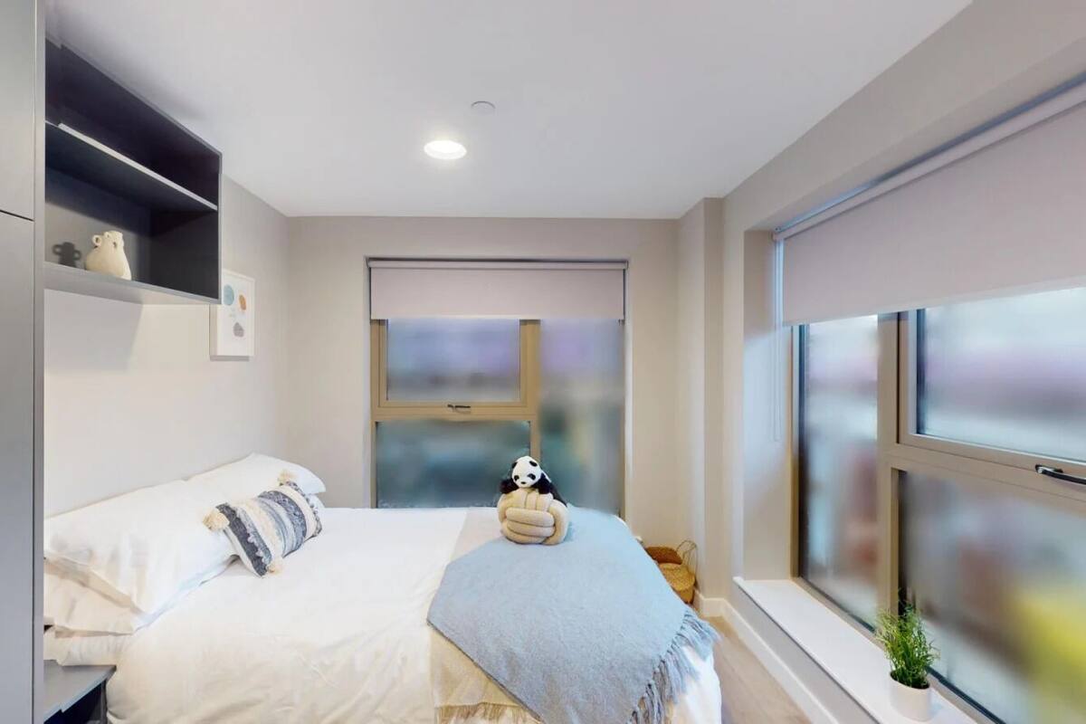Quarto moderno com cama, janela e estantes embutidas.