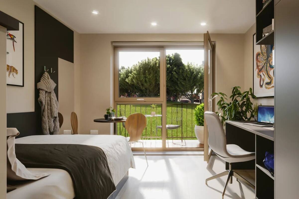 Quarto moderno com cama, escrivaninha e varanda com área de estar externa.