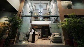 Um lobby moderno com balcão de recepção, área de estar e escada para um andar superior.