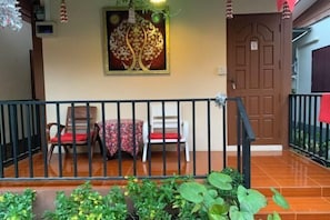 Varanda com duas cadeiras, uma mesa e um objeto decorativo na parede.