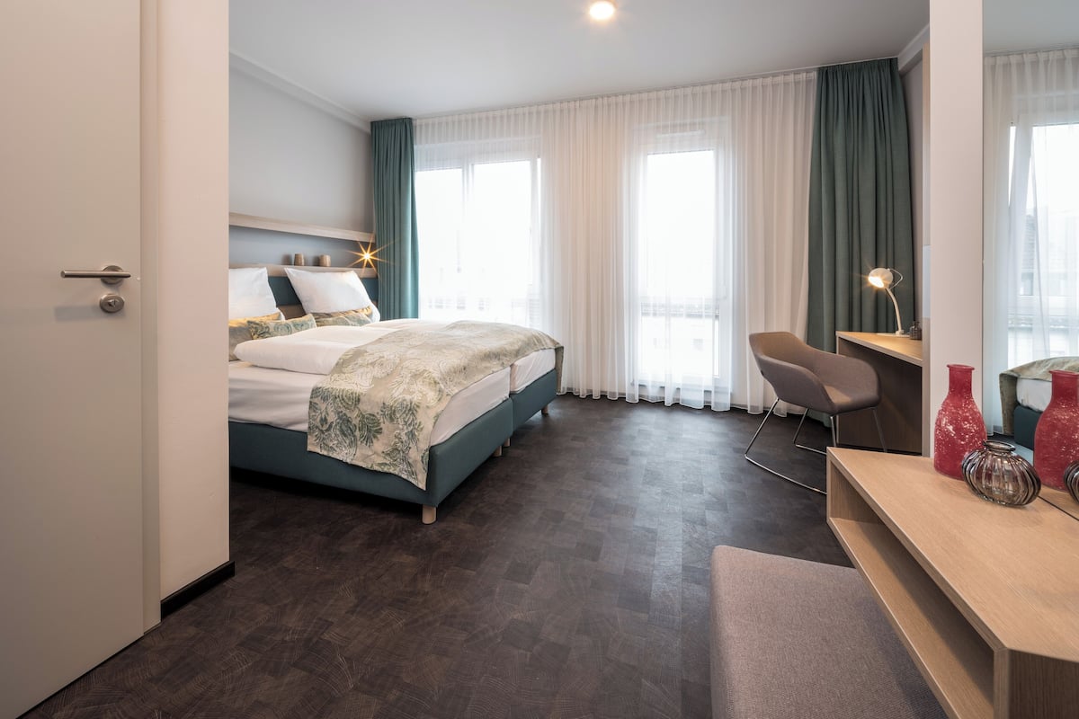 Quarto de hotel moderno com uma cama, uma escrivaninha e uma cadeira.