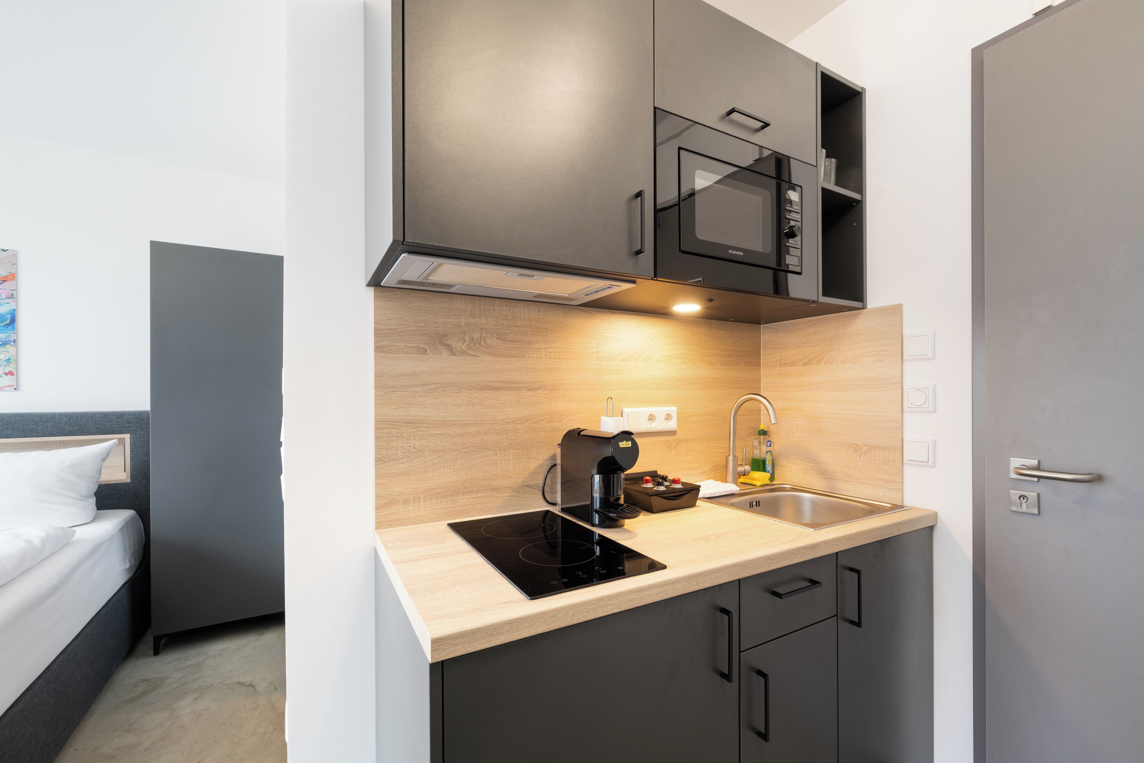 Uma cozinha compacta equipada com micro-ondas, cafeteira e pia.