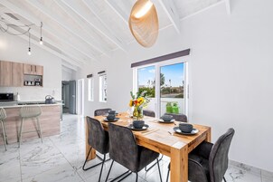 Uma cozinha moderna com armários de madeira, bancada de mármore e área de jantar com mesa e cadeiras de madeira.