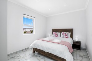 Um quarto com uma cama grande, uma mesa de cabeceira, uma janela com vista e uma luminária no teto.