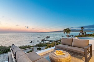 Terraço à beira-mar com sofá e mesa redonda, com vista para o oceano e uma piscina privativa.
