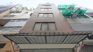 Um edifício de vários andares com telhado plano, várias janelas e um aparelho de ar condicionado visível.
