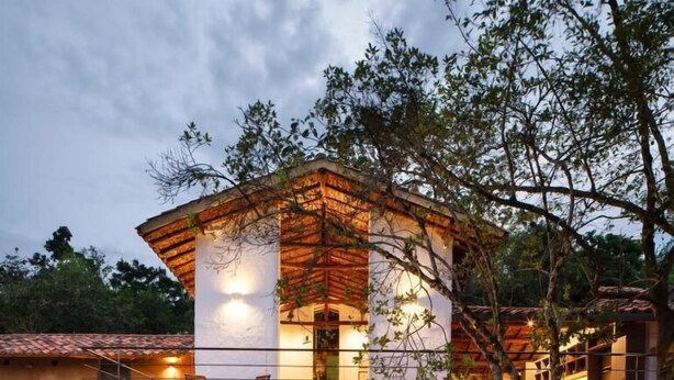 Uma casa moderna com fachada de pedra, pérgola de madeira e lareira de pedra.