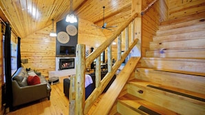 Um interior de madeira com escadas, lareira e um sofá.