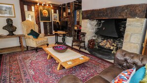 Uma sala de estar aconchegante com lareira, um tapete estampado, um sofá de couro e uma mesa de centro de madeira.