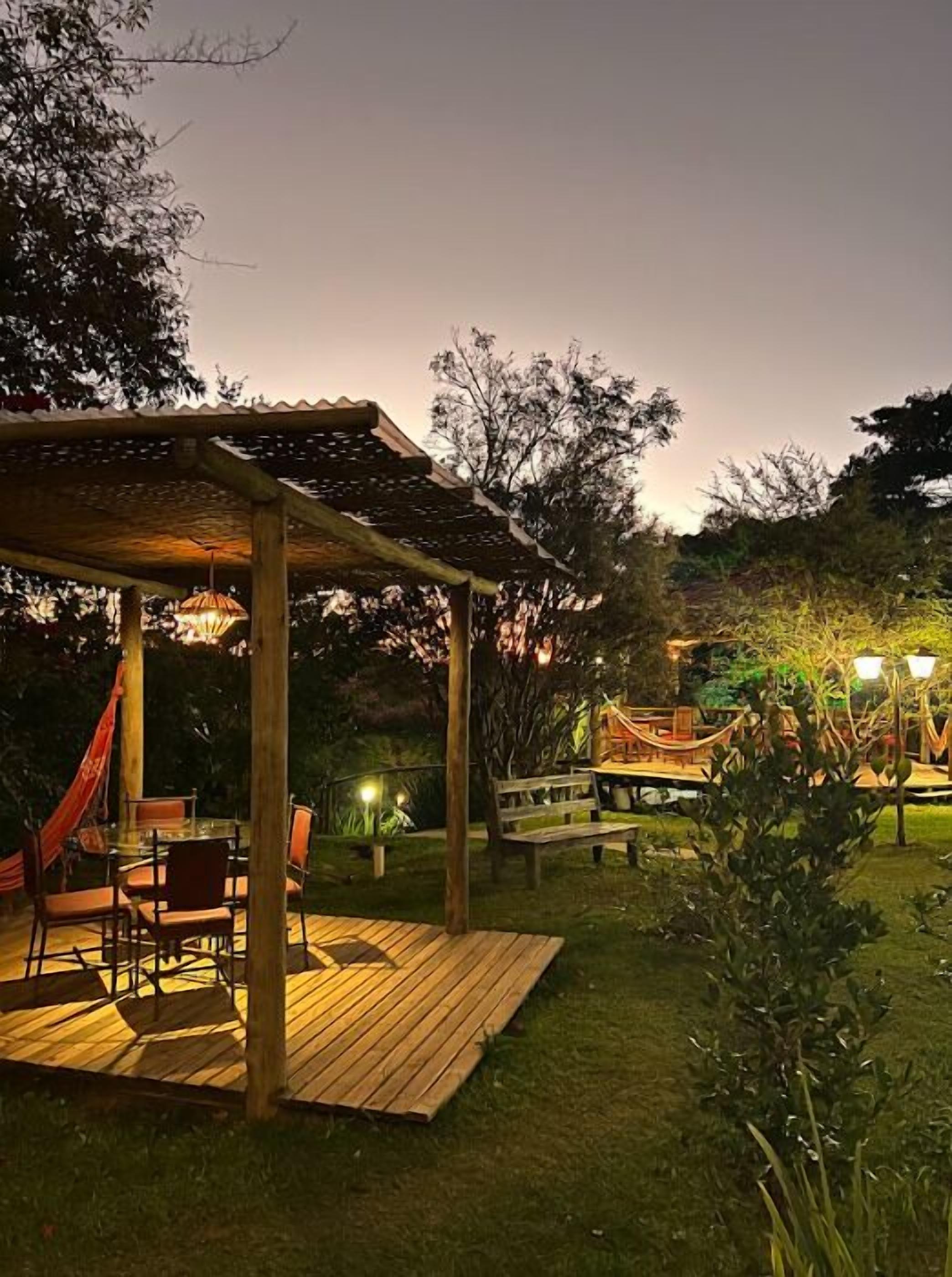 Um deck de madeira com pérgola, área de estar externa e uma rede.