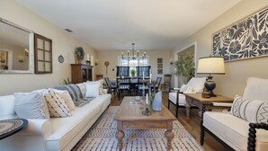 Uma sala de estar com sofá, mesa de centro e uma área de refeições com cadeiras e mesa.