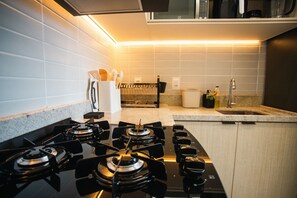 Uma cozinha moderna com fogão a gás, cafeteira e pia.
