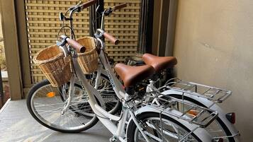 Uma bicicleta com cesto e selim de couro encostada a uma parede com padrão de treliça.