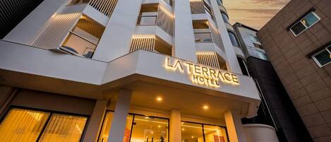 Um hotel moderno com entrada imponente, grandes janelas e fachada bem iluminada.