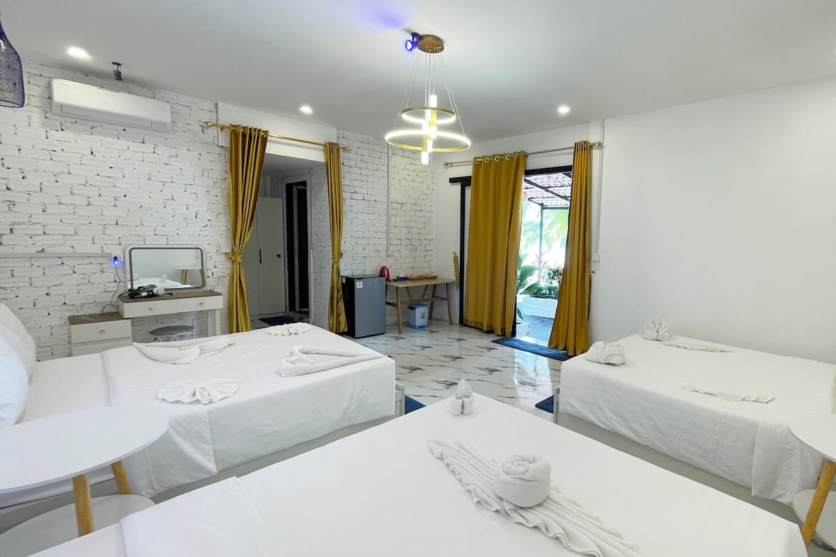 Quarto de hotel com duas camas, uma pequena mesa, um espelho e uma janela com cortinas.