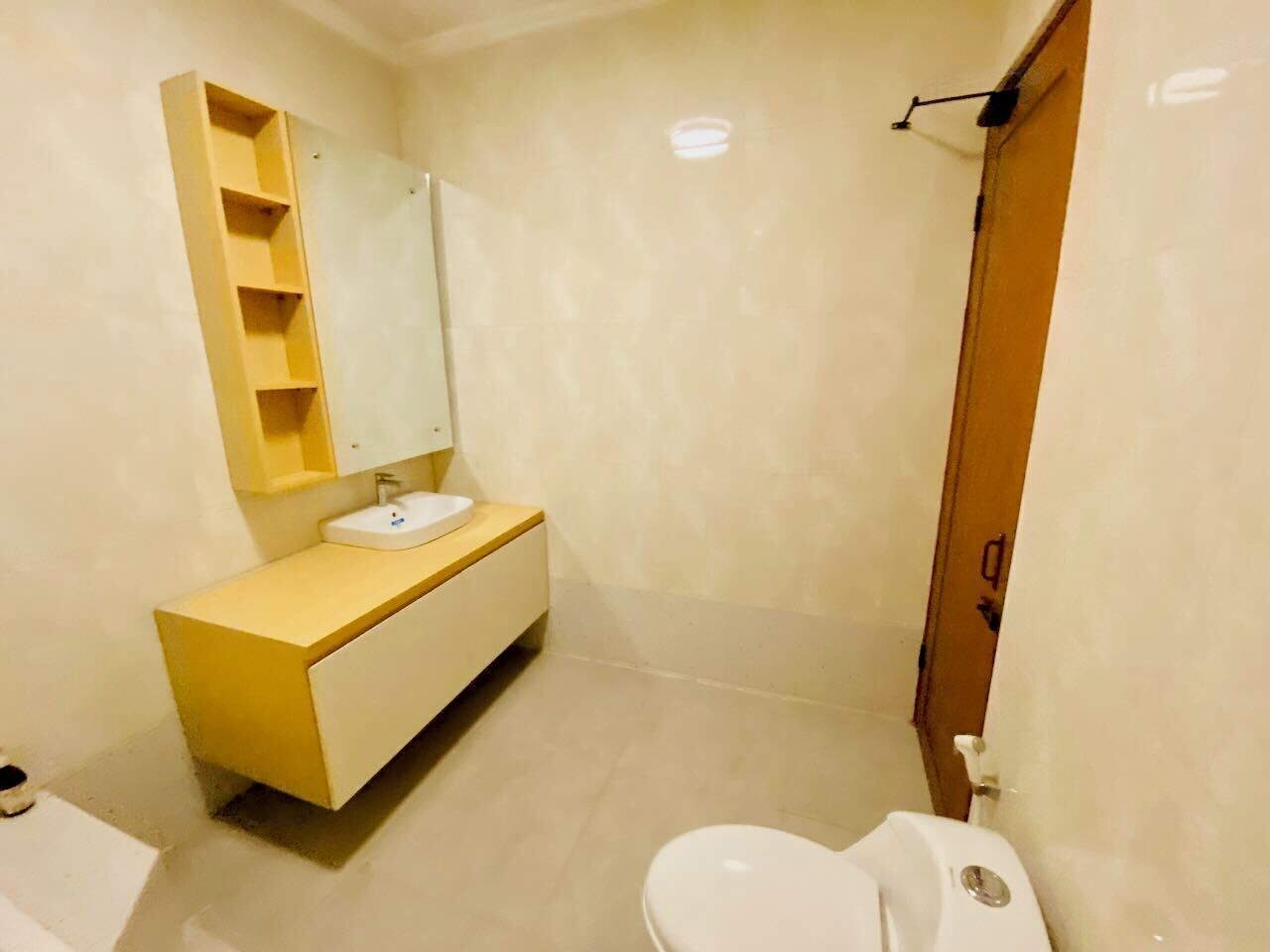 Uma casa de banho moderna com toucador de madeira, lavatório e sanita.