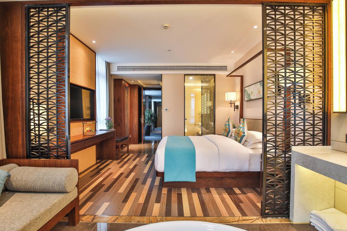 Quarto de hotel com cama, sofá, escrivaninha e banheiro.