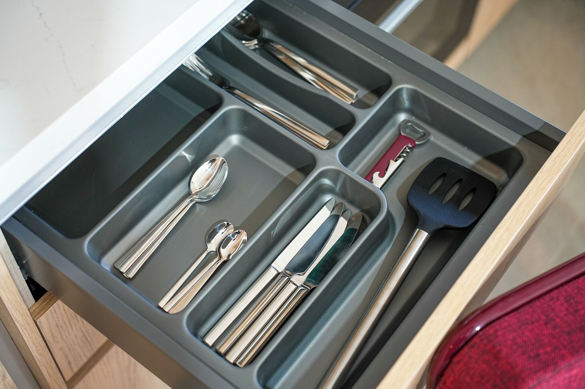 Uma gaveta com divisórias, contendo diversos utensílios.