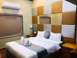 Quarto de hotel com cama, mesa de cabeceira, ar condicionado fixado na parede e janela com persianas.