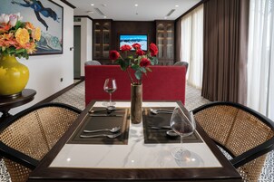 Uma área de refeições com uma mesa posta para dois, um vaso com rosas vermelhas e um quadro na parede.