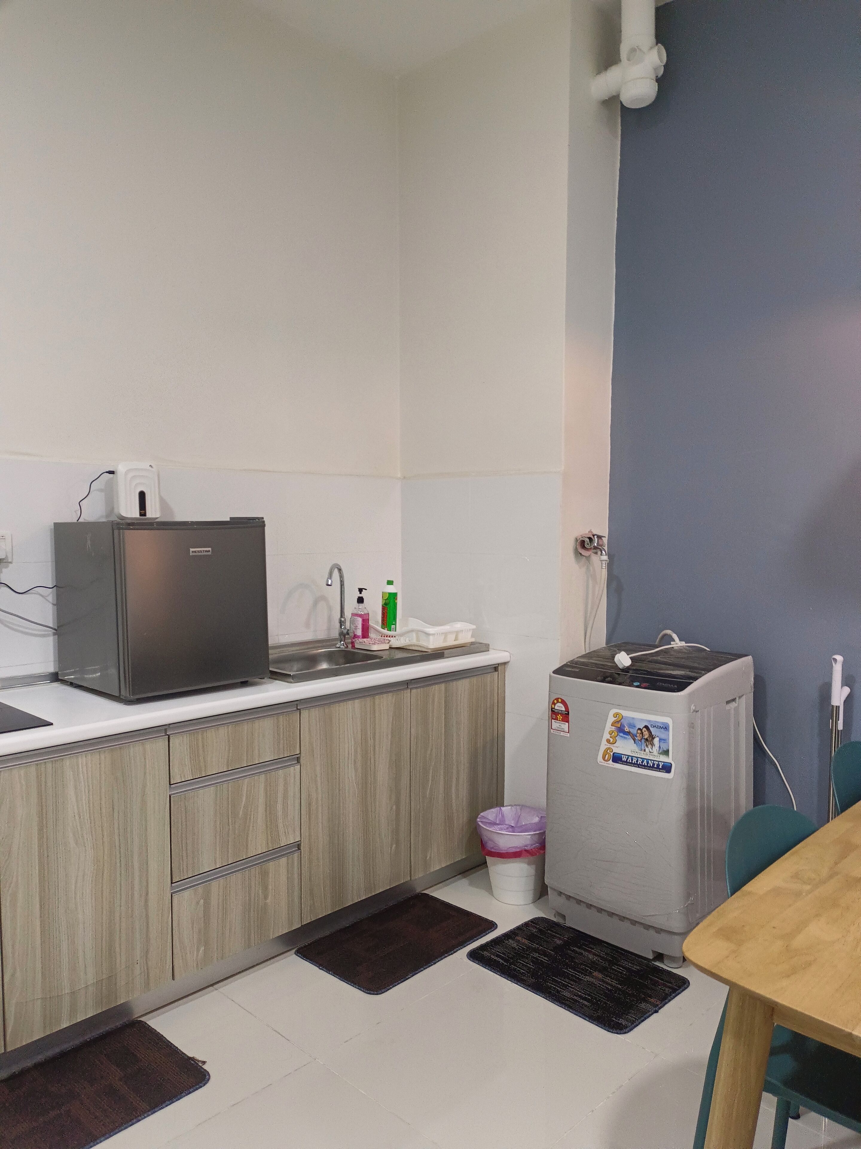 Uma cozinha compacta com geladeira, micro-ondas, pia e um pequeno dispensador de água.
