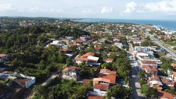 Vista aérea de uma área residencial com casas, ruas e uma orla costeira.